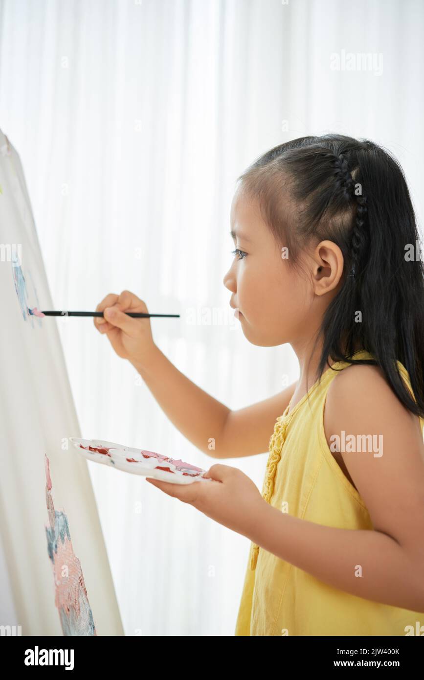 Little talented Asian girl concentrated on painting Stock Photo - Alamy