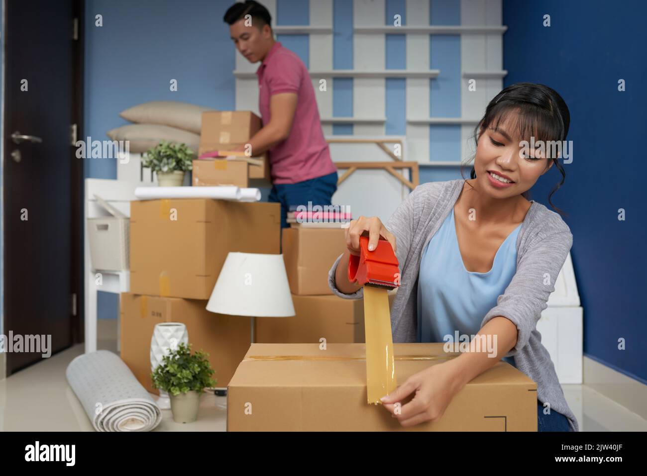 Young Asian couple packing home stuff while while moving in new home ...
