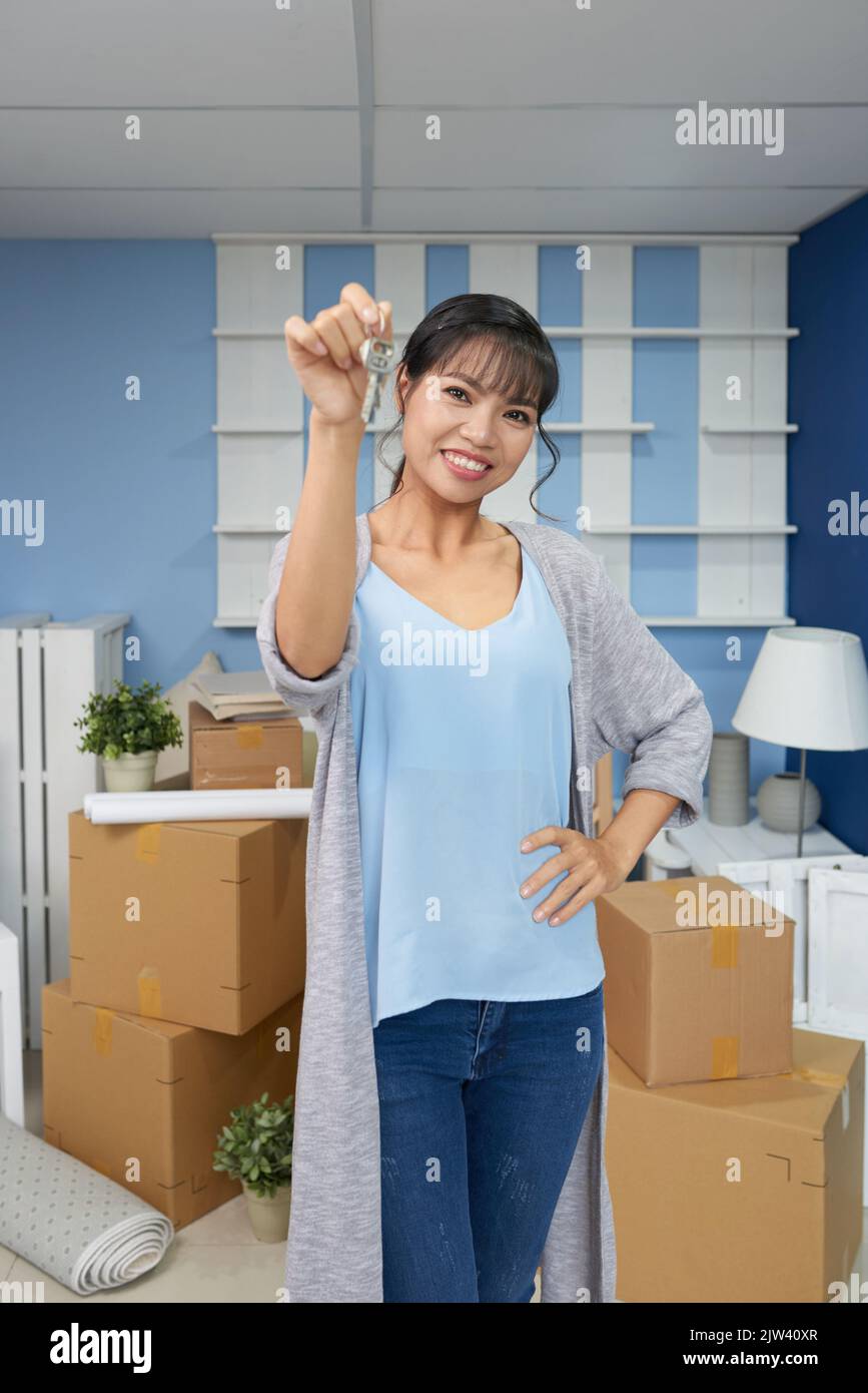 Portrait of young pretty Asian woman standing in new apartment with ...