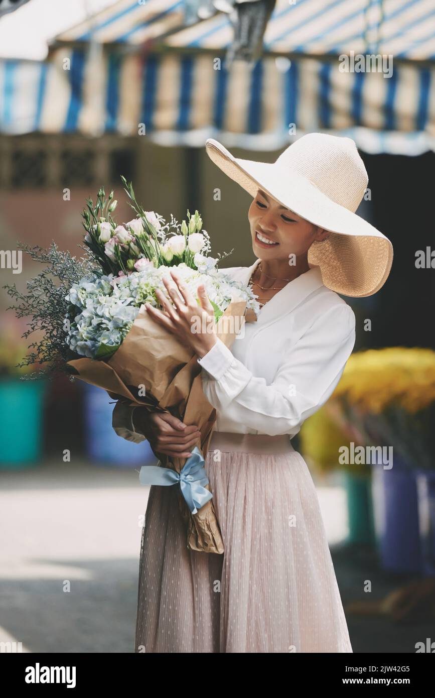 Smiling young Asian woman enjoying beauty of flowers in her hands Stock ...