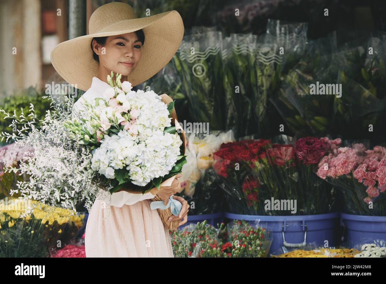 Charming smiling lady with flowers standing at market counter Stock ...