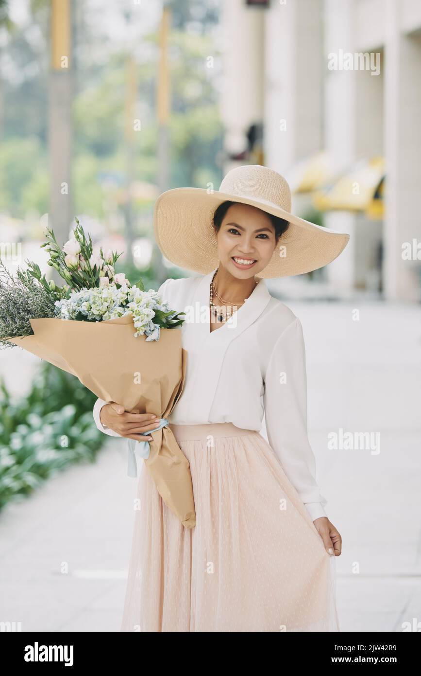 Lovely pretty smiling woman in light clothes holding bouquet of flowers ...