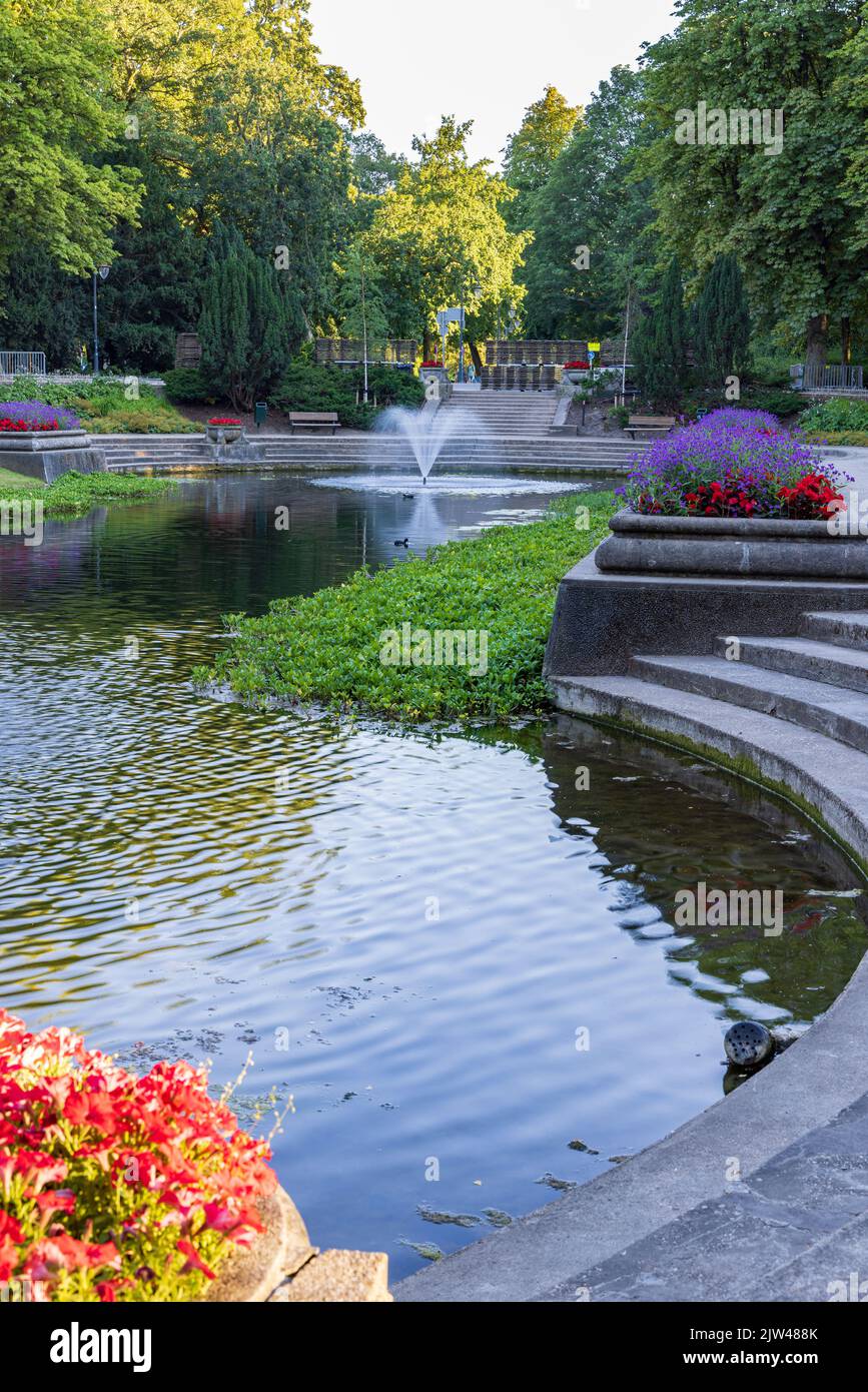 Fountains and large classic pond surrounded with flowers in public park ...