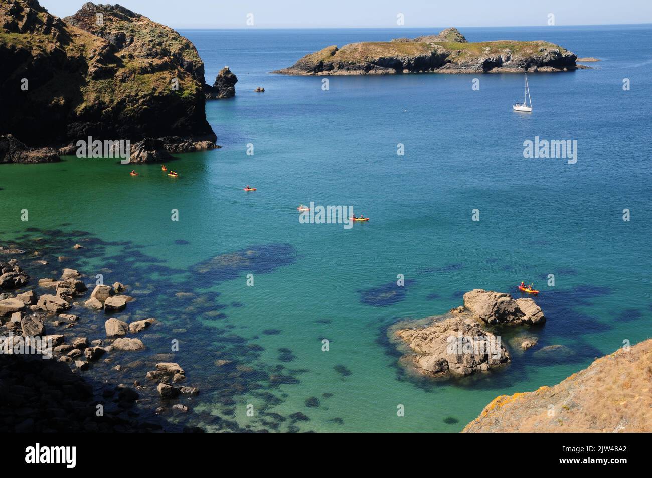 Kayaks paddle calm, clear water near Mullion Cove, Cornwall, with ...