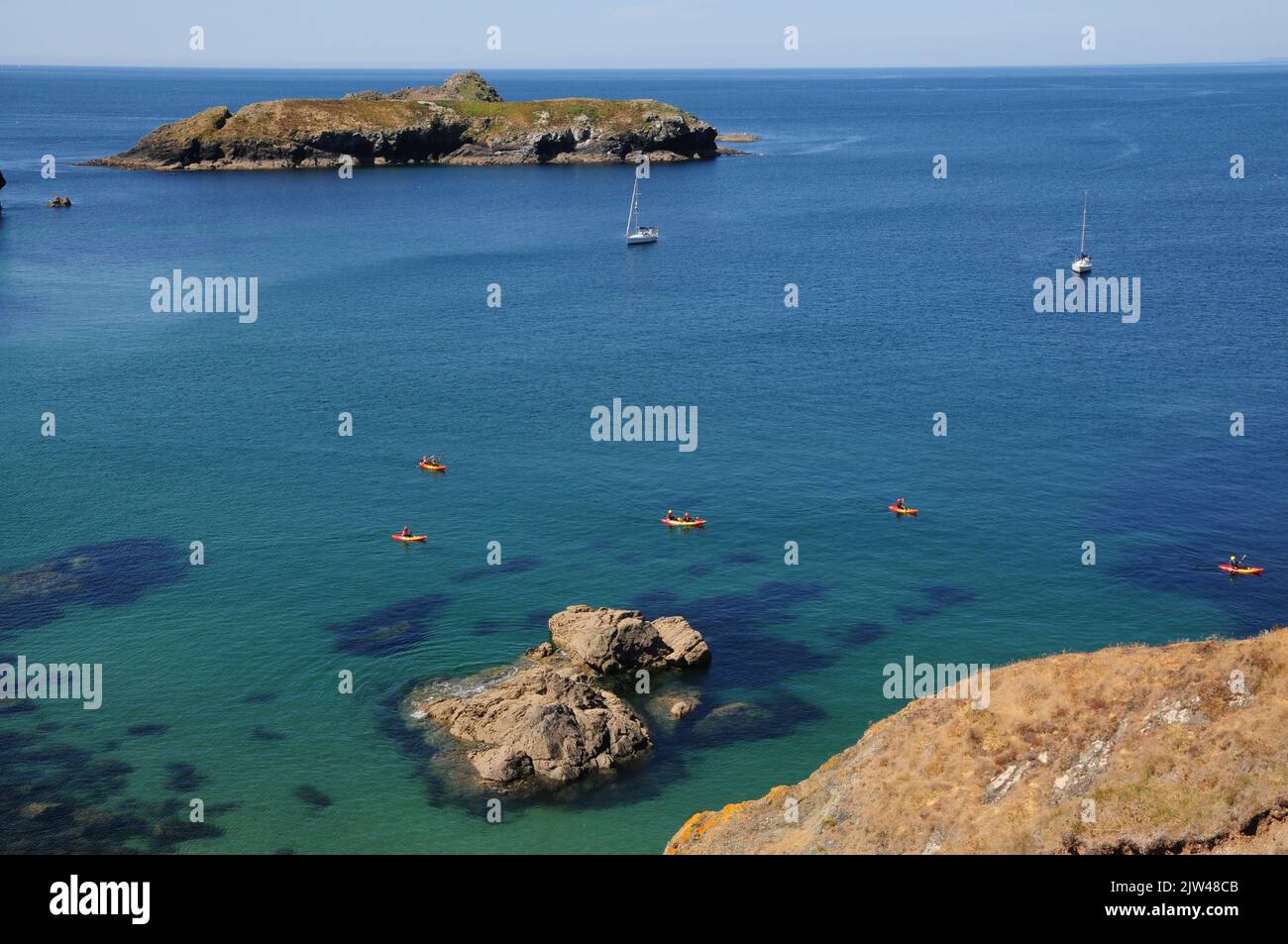 Kayaks paddle calm, clear water near Mullion Cove, Cornwall, with ...