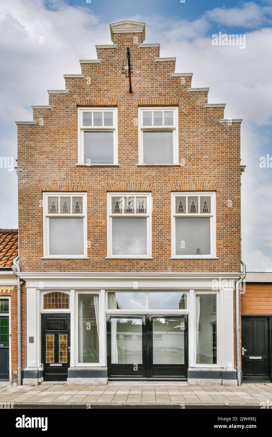 The front view of a brick building with signs,pavement and wooden doors ...