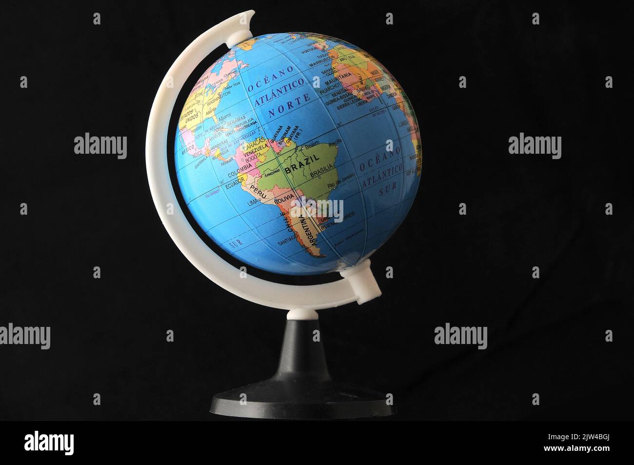 A shot of a small replica of the globe on a stand with a black ...
