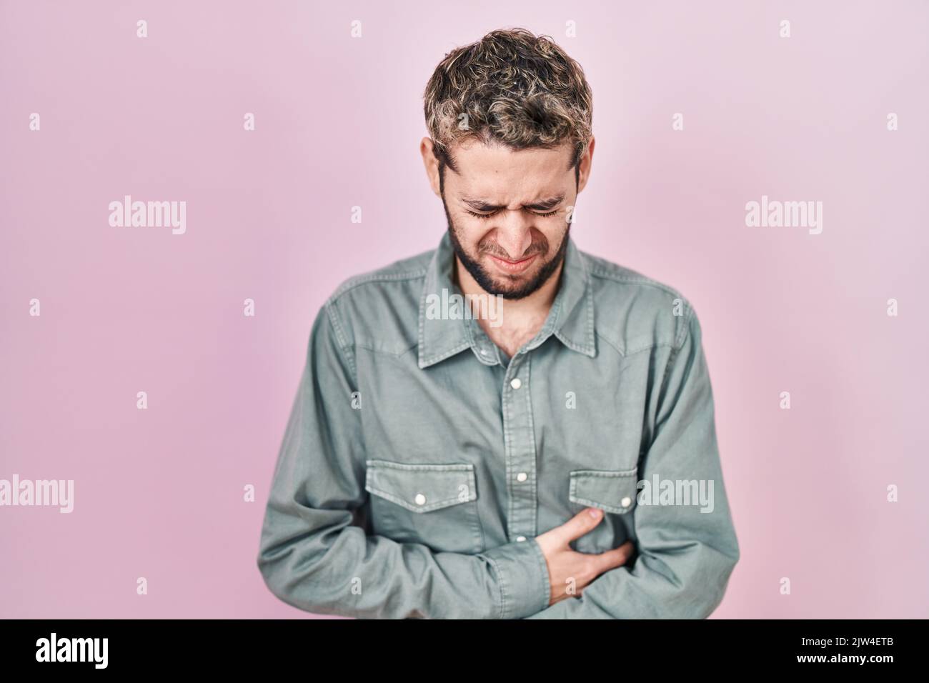 Hispanic man with beard standing over pink background with hand on ...