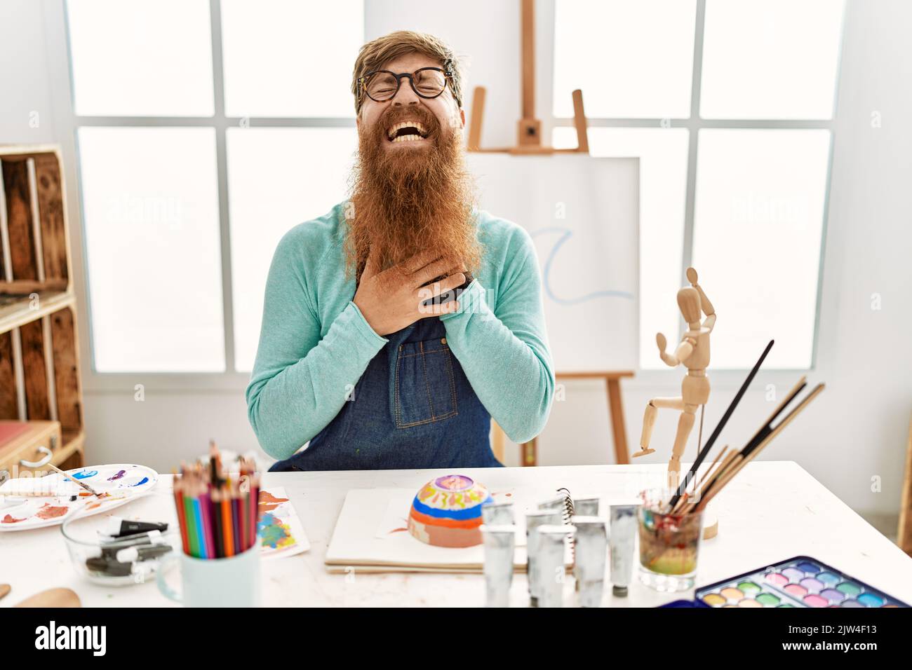 Redhead man with long beard painting clay bowl at art studio shouting ...