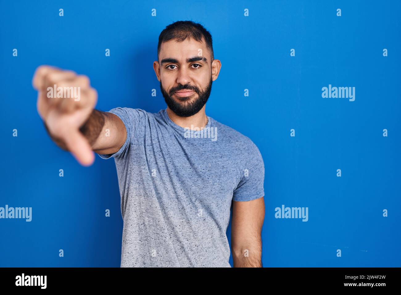Middle east man with beard standing over blue background looking ...