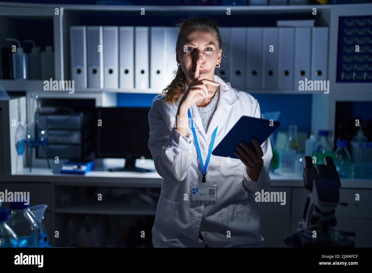 Beautiful blonde woman working at scientist laboratory late at night ...