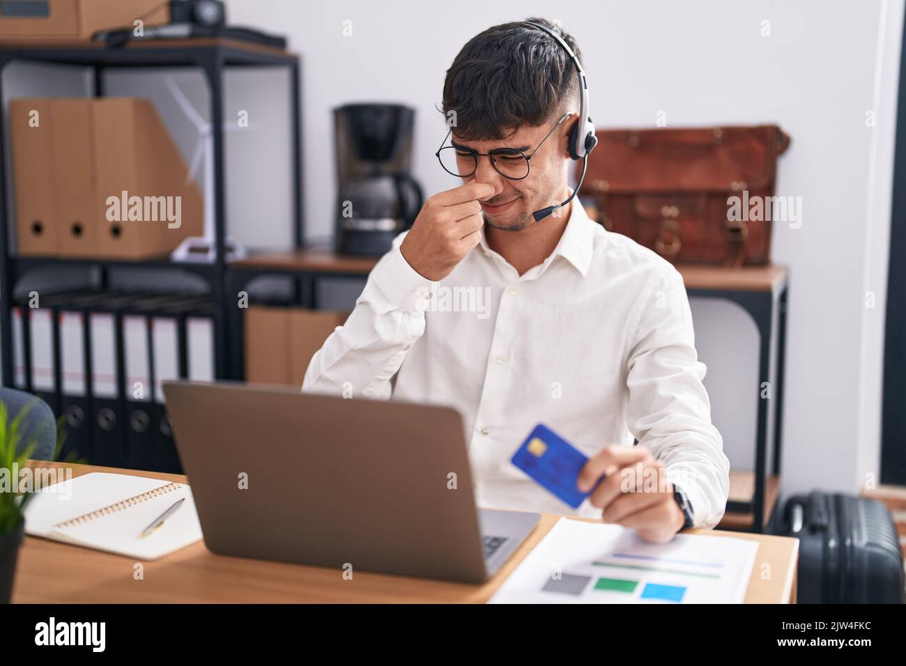 Young hispanic man working using computer laptop holding credit card ...