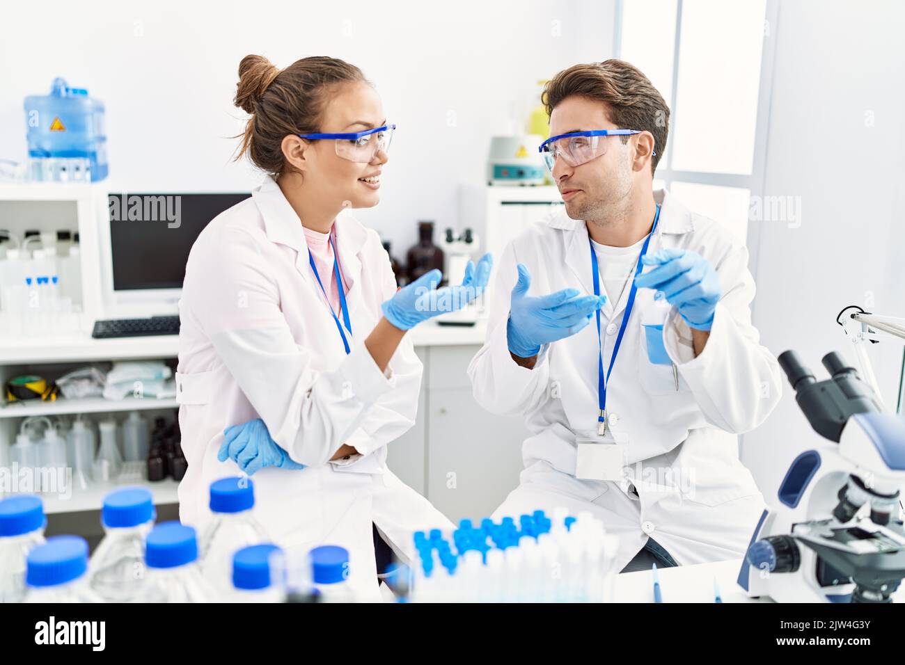 Man and woman wearing scientist uniform holding sample talking at ...