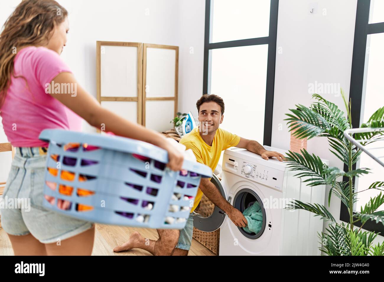 Man and woman couple cleaning clothes using washing machine at laundry ...