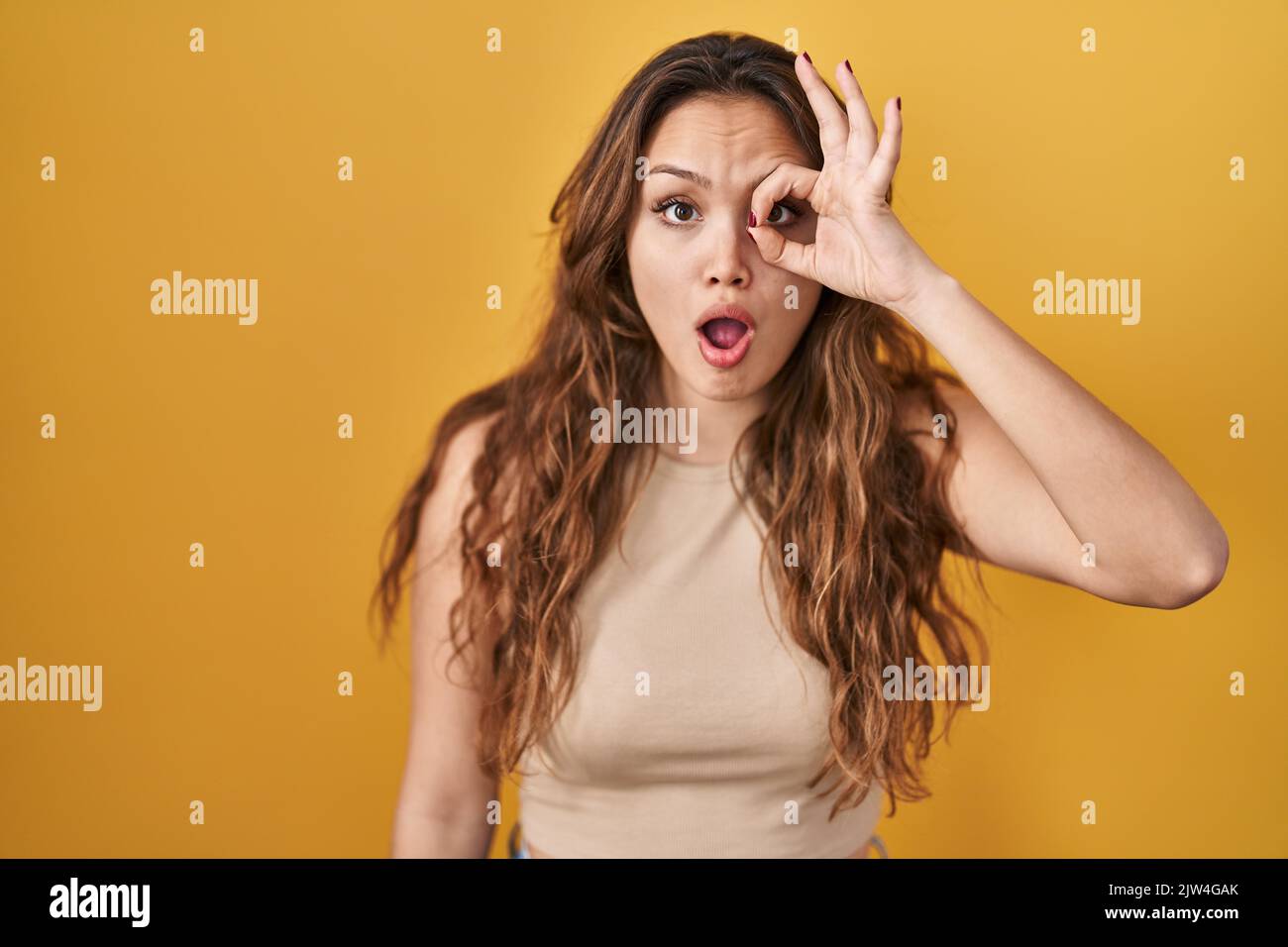 Young hispanic woman standing over yellow background doing ok gesture ...