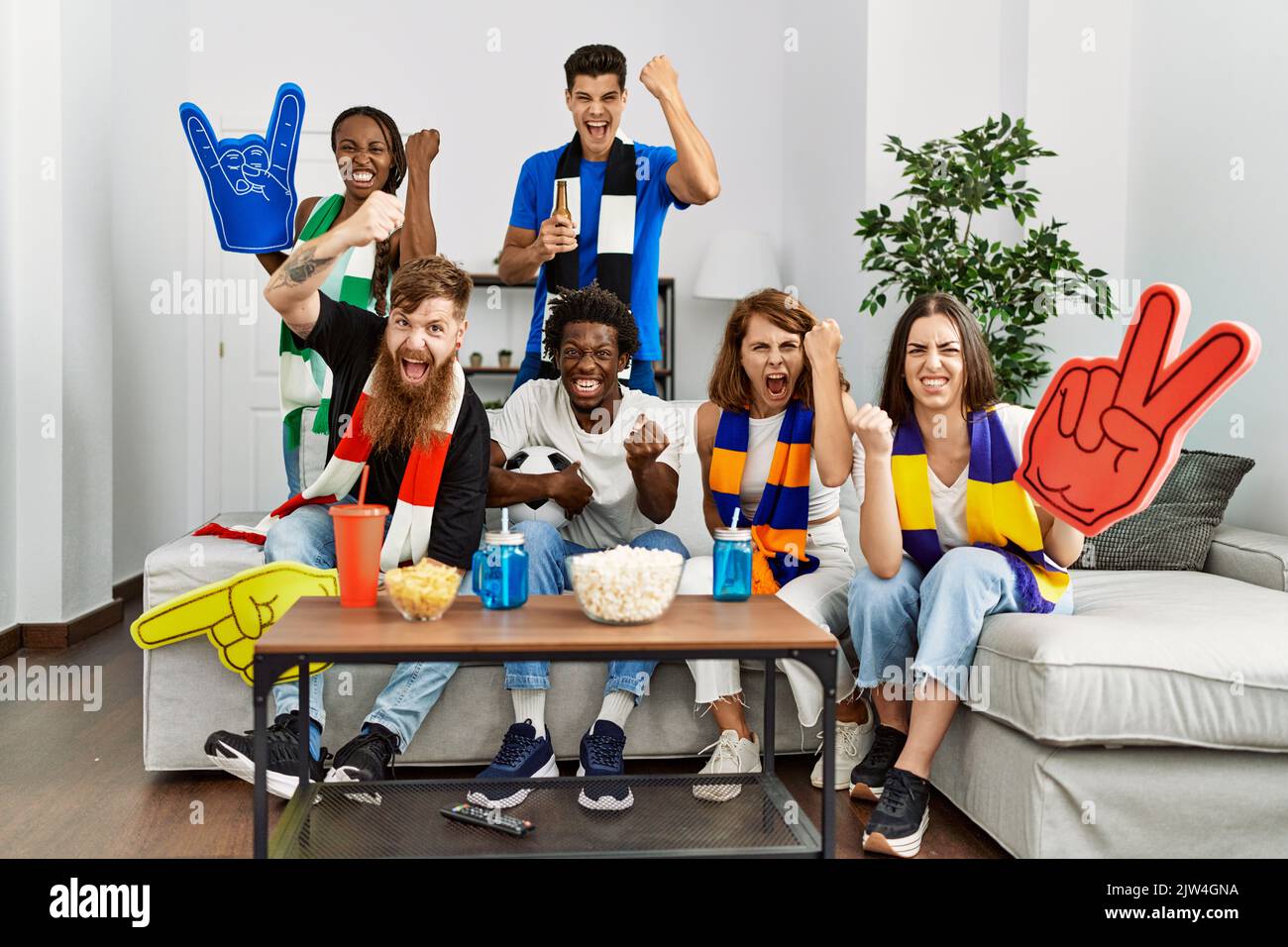 Group of friends supporting football team watching tv al home sitting ...