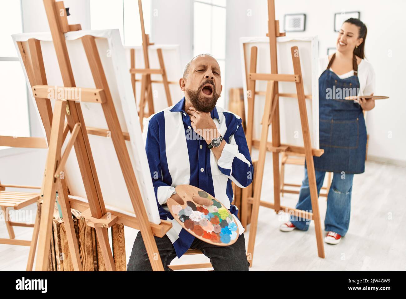Senior artist man at art studio touching painful neck, sore throat for ...
