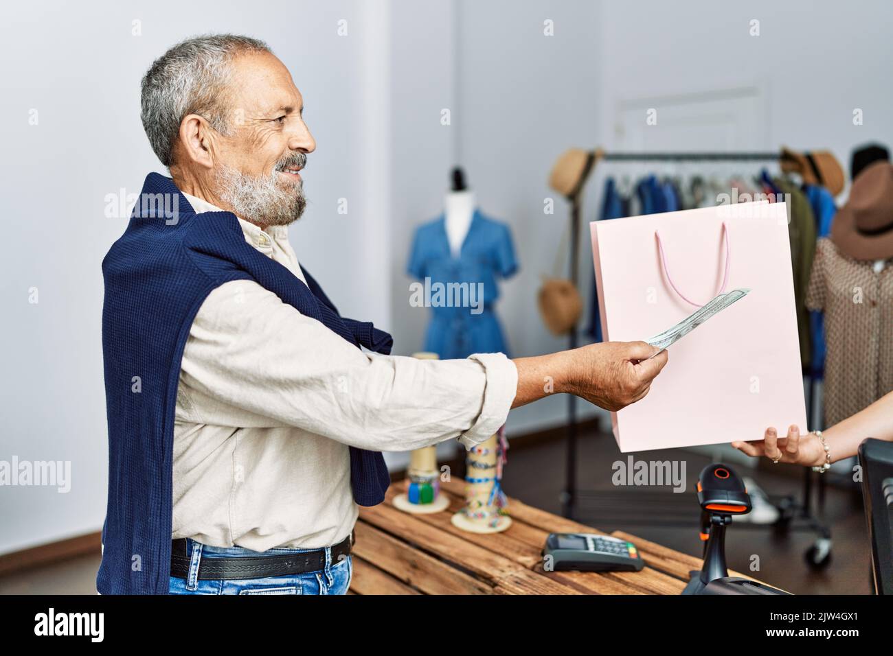 Senior grey-haired man paying for purchase at clothing store Stock ...