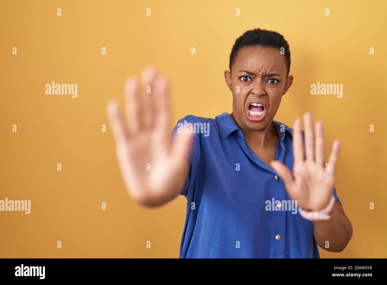 African american woman standing over yellow background afraid and ...
