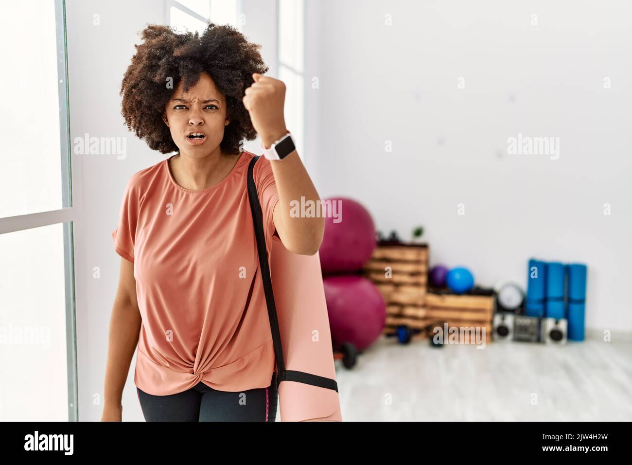 African american woman with afro hair holding yoga mat at pilates room ...