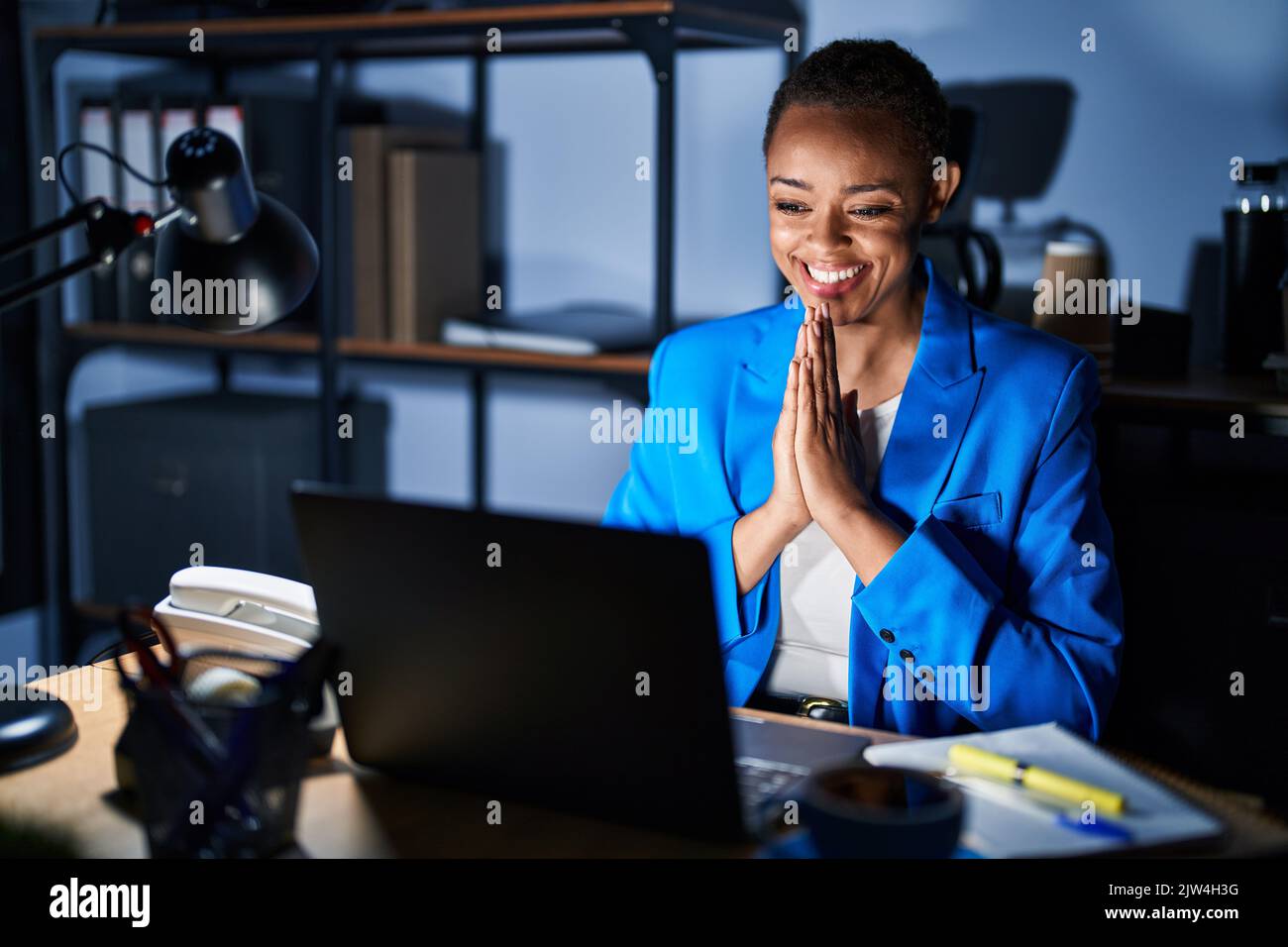 Beautiful african american woman working at the office at night praying ...
