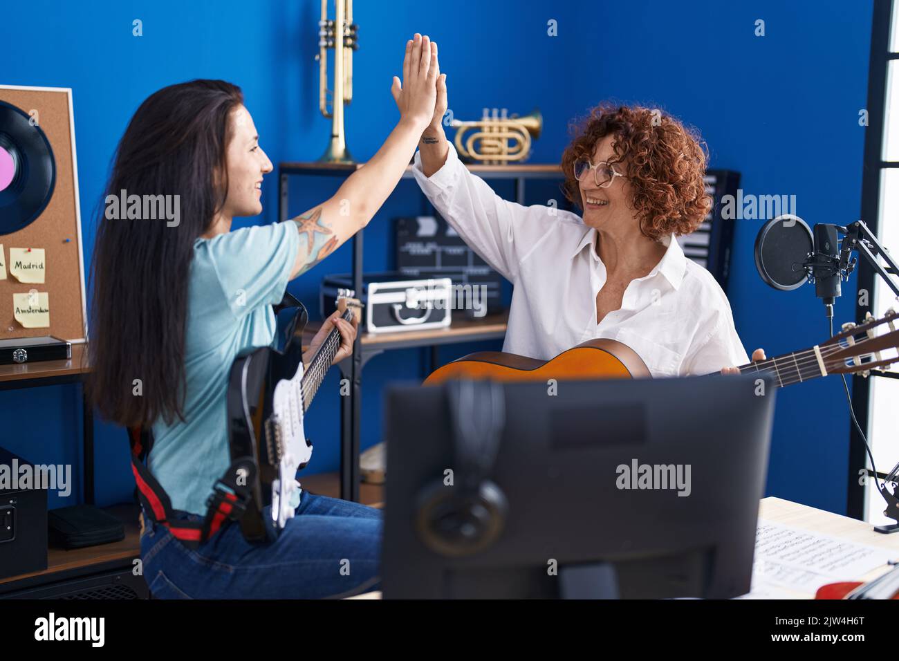 Two women guitarist high five with hands raised up at music studio ...