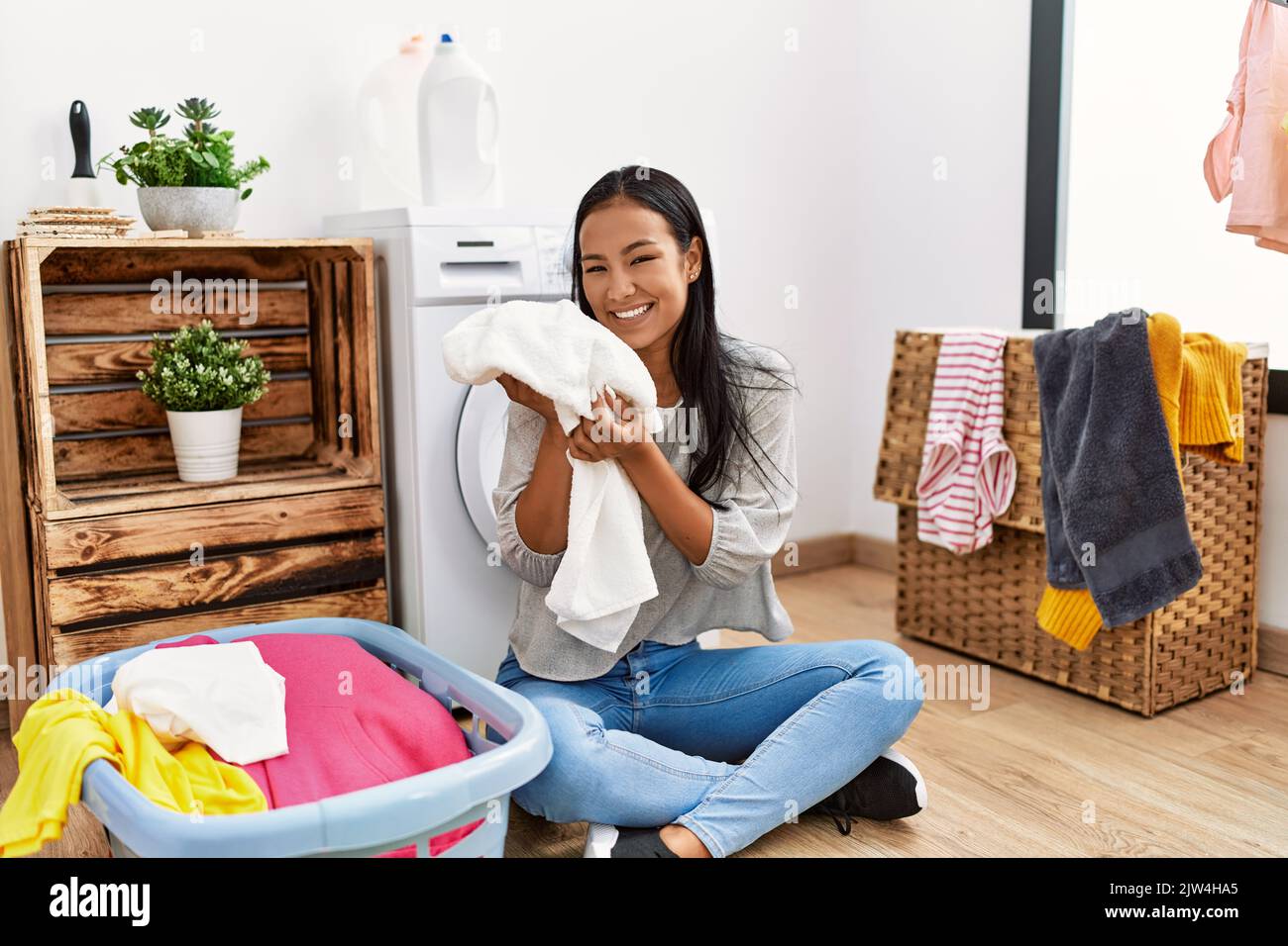 Young latin woman smelling clothes at laundry room Stock Photo - Alamy