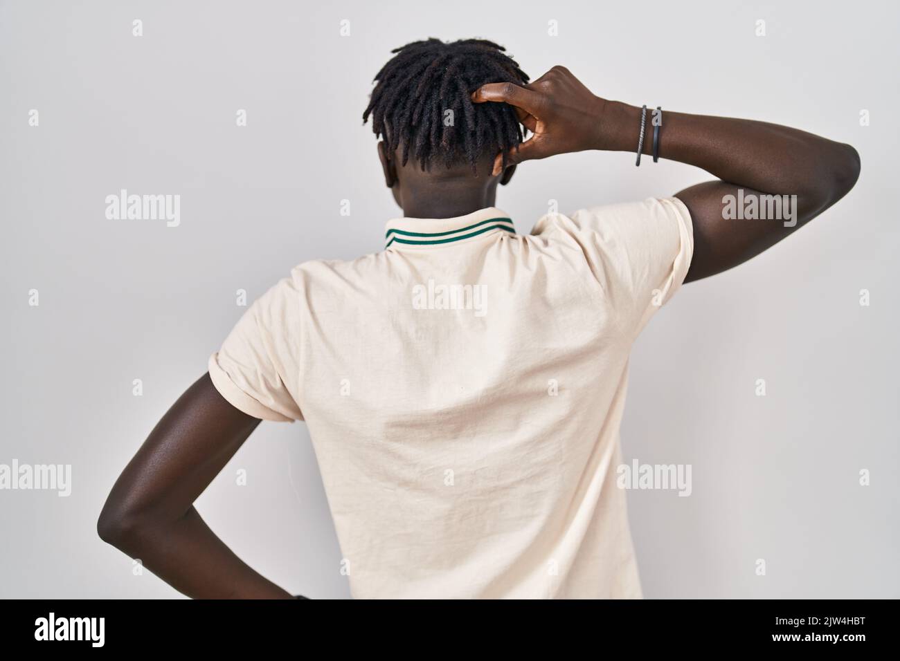 African man with dreadlocks standing over isolated background backwards ...