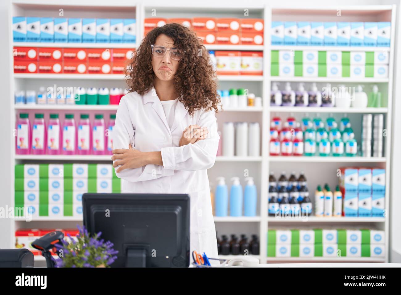 Hispanic woman with curly hair working at pharmacy drugstore depressed ...