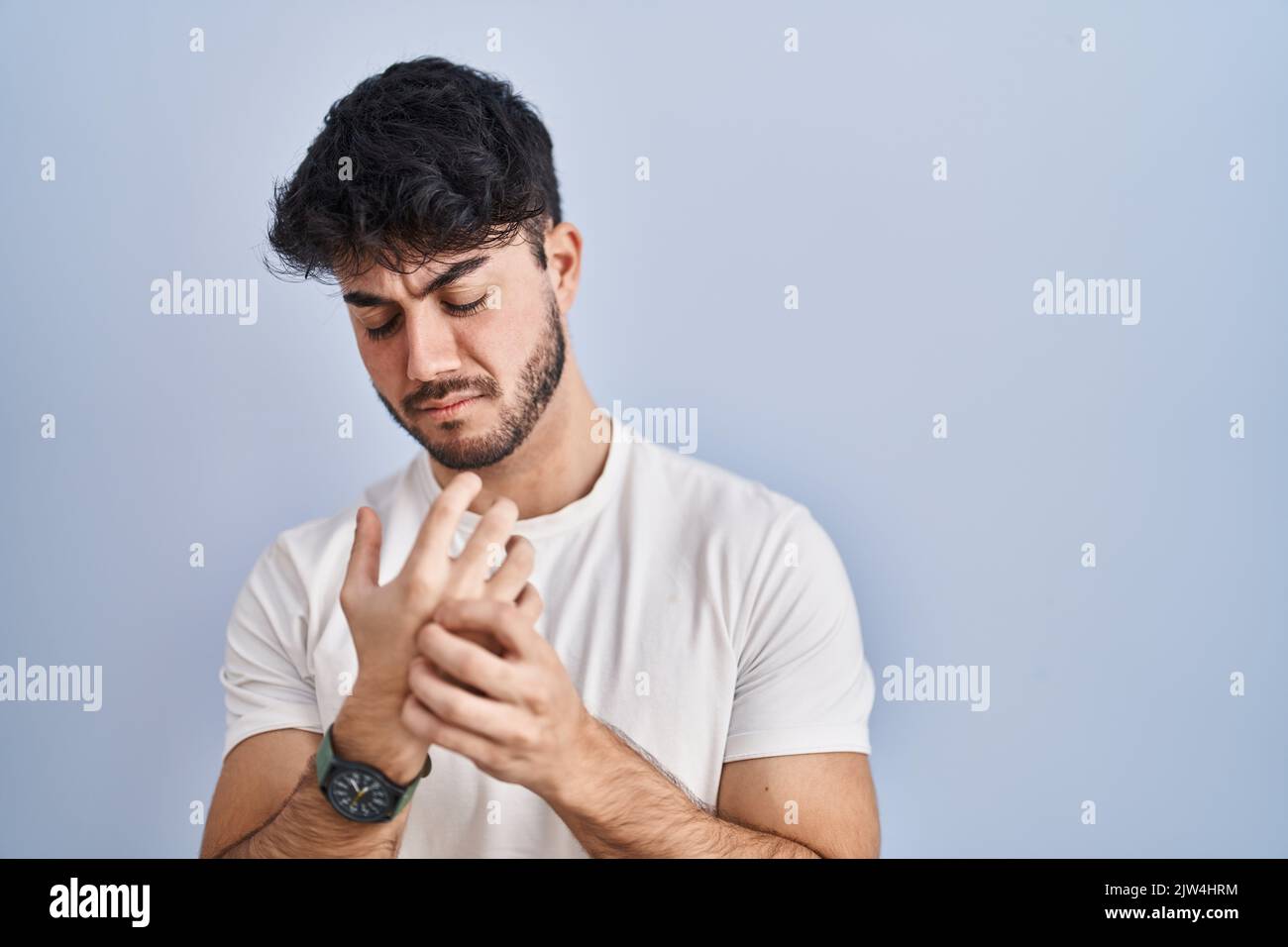 Hispanic man with beard standing over white background suffering pain ...
