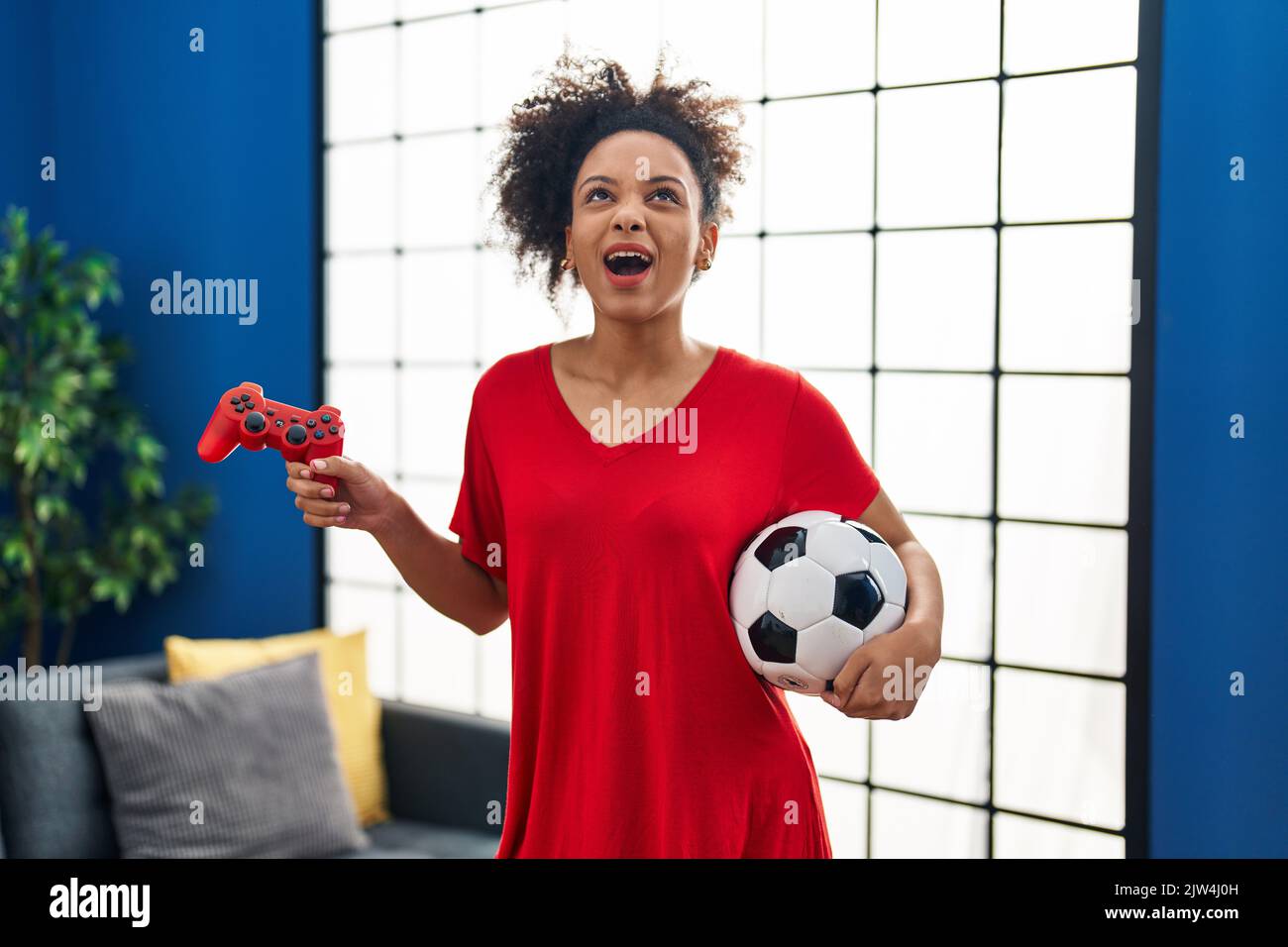 Young african american woman playing football video game angry and mad ...