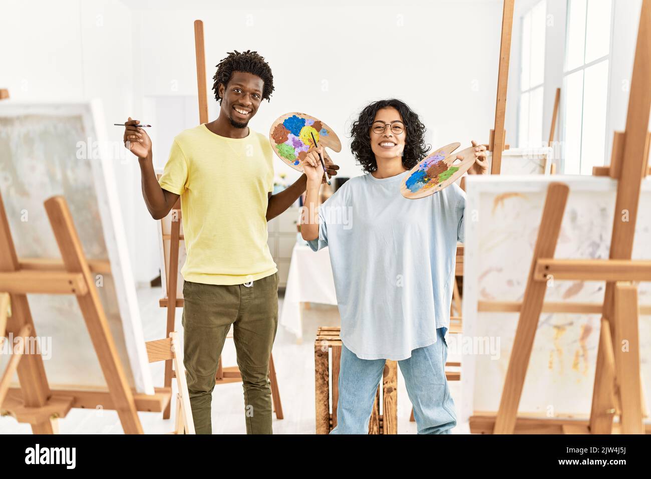 African american artist couple smiling happy holding paintbrush and ...