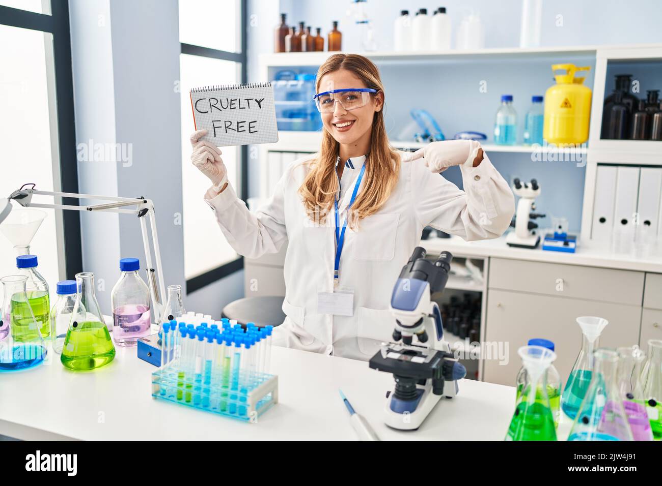 Young blonde scientist woman working on cruelty free laboratory pointing finger to one self ...