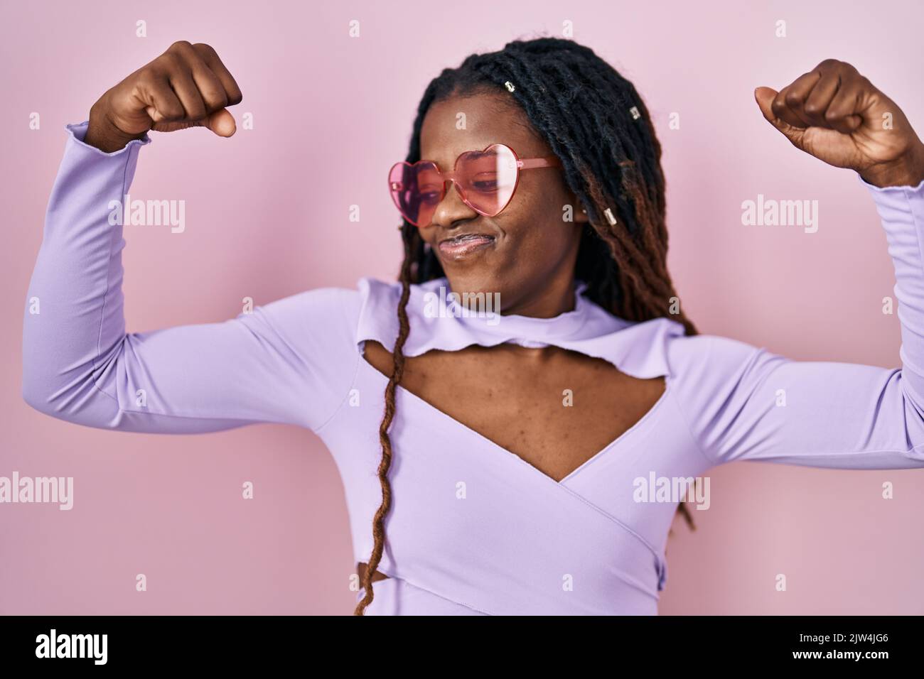African woman with braided hair standing over pink background showing ...