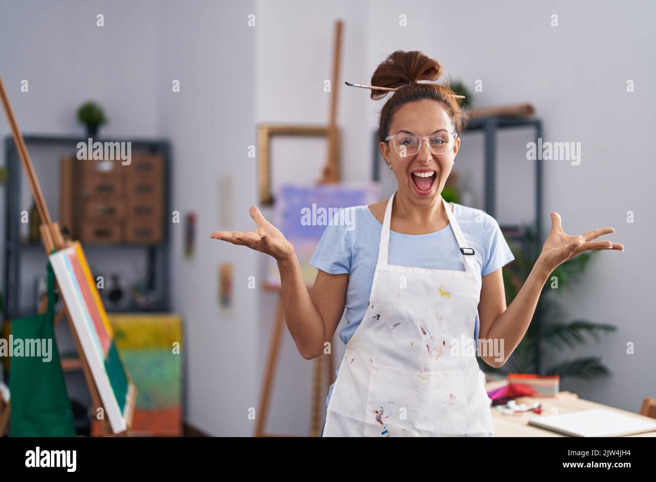 Brunette woman painting at art studio celebrating victory with happy ...