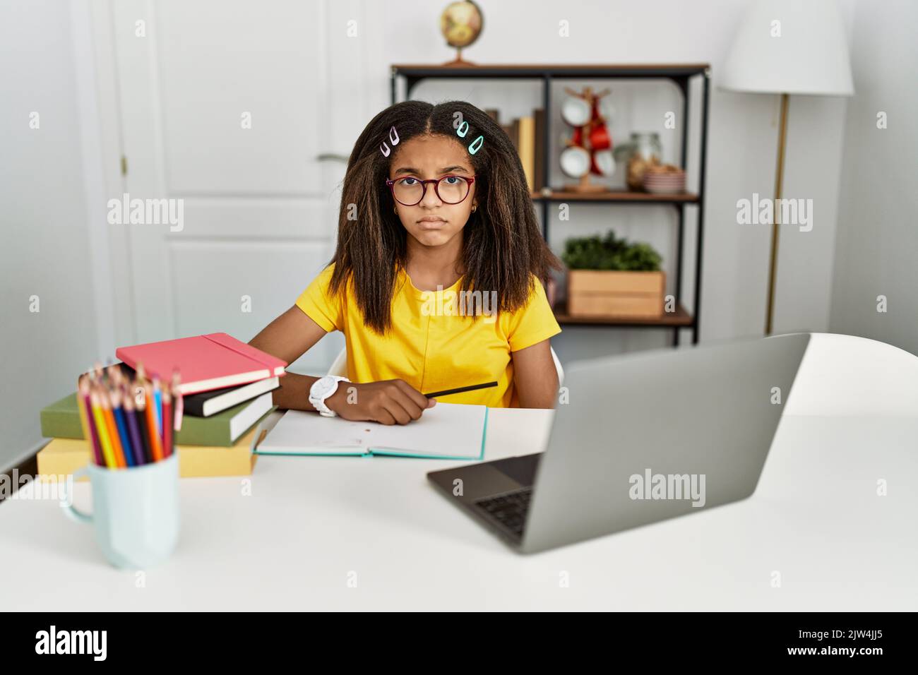 Young african american girl doing homework at home depressed and worry ...