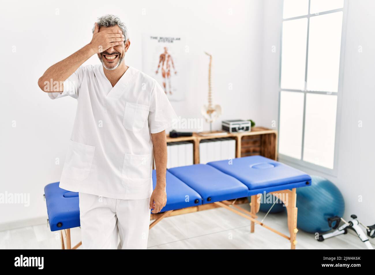 Middle age hispanic therapist man working at pain recovery clinic ...