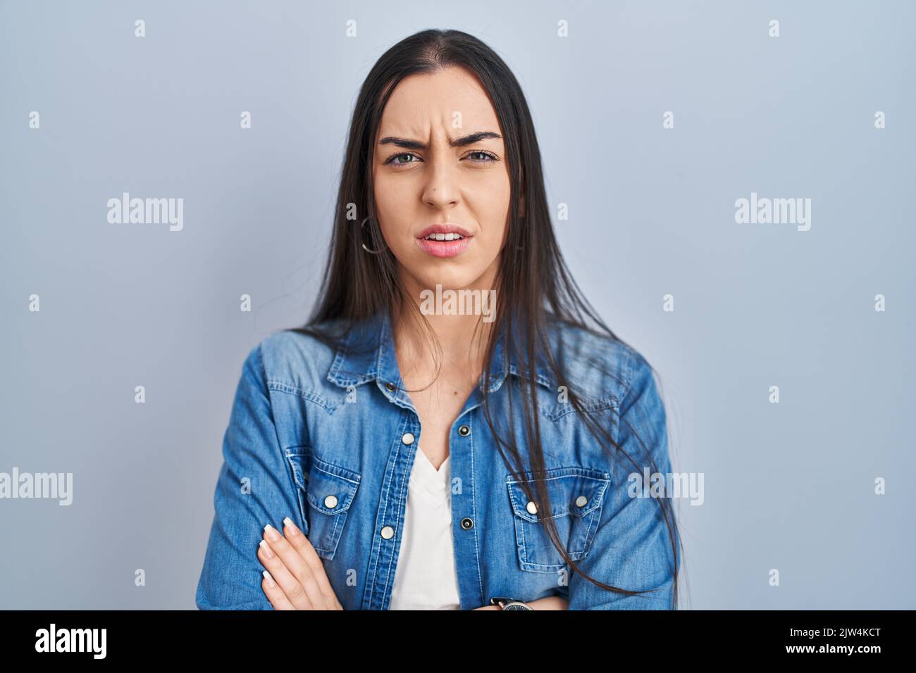 Hispanic woman standing over blue background skeptic and nervous ...