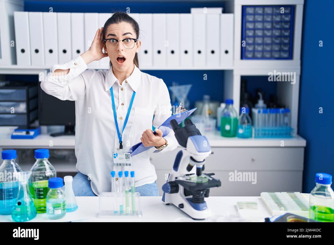 Young brunette woman working at scientist laboratory crazy and scared ...