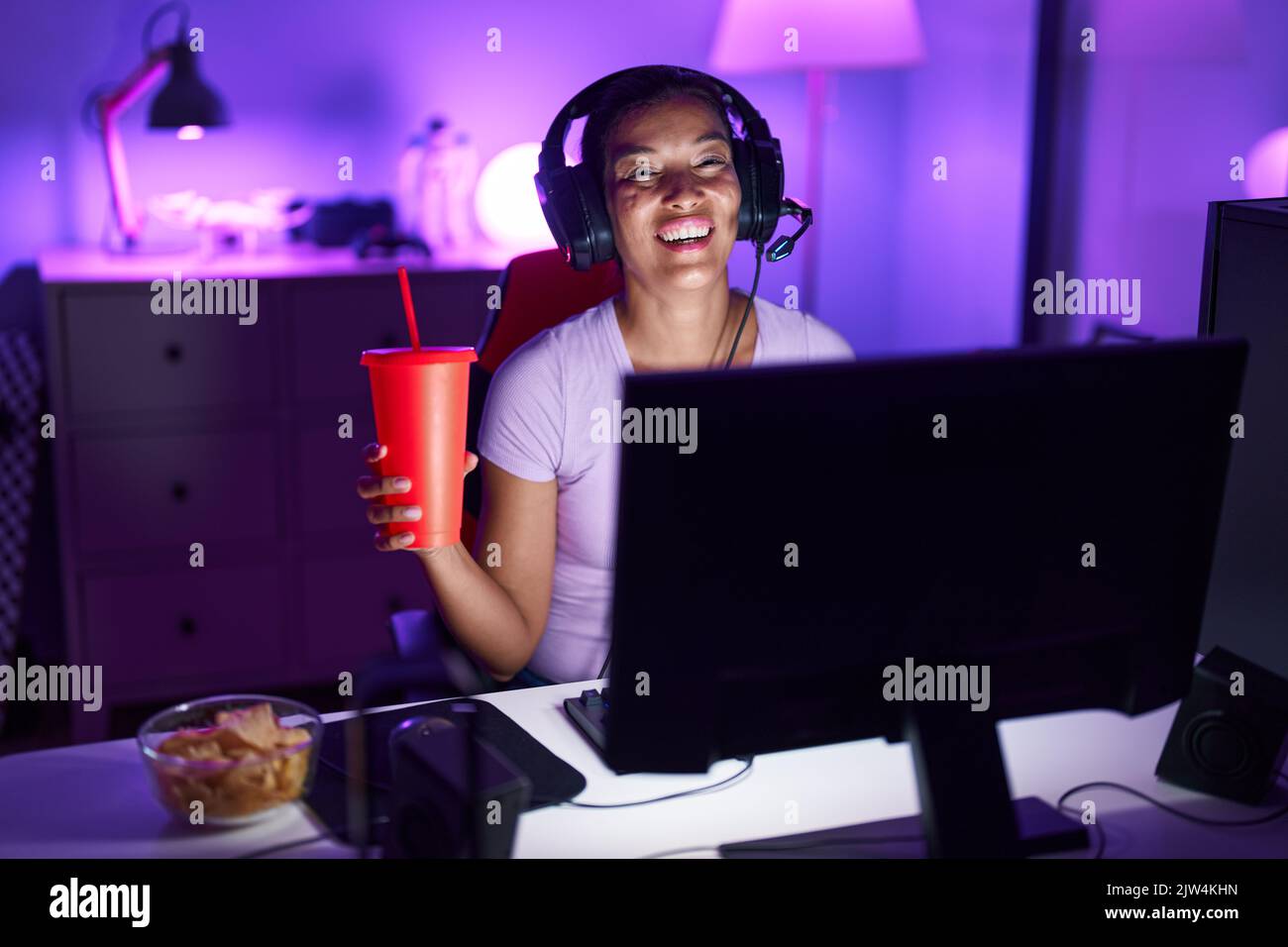 Young beautiful hispanic woman streamer playing video game at gaming ...