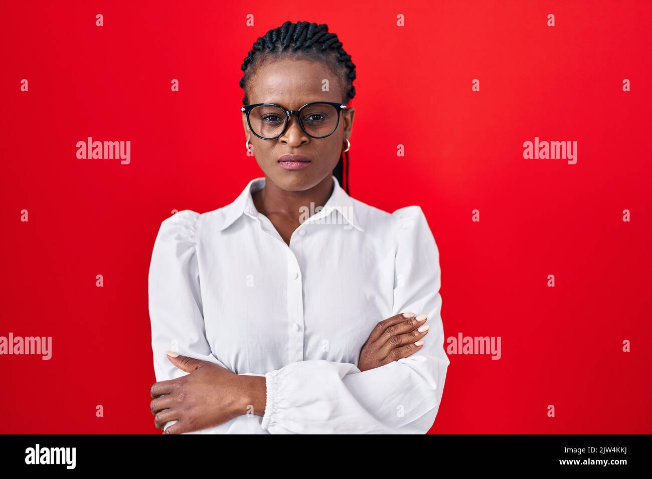 African woman with braids standing over red background skeptic and ...
