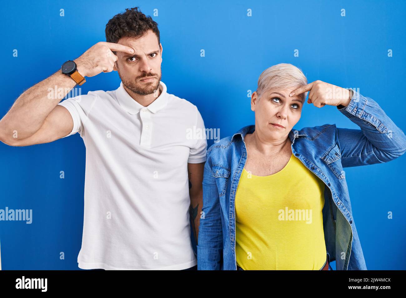 Young brazilian mother and son standing over blue background pointing ...