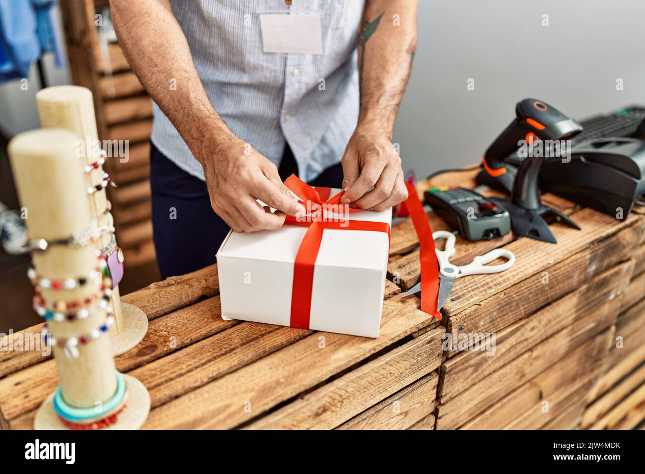 Hands of shopkeeper man preparing gift at clothing store Stock Photo ...