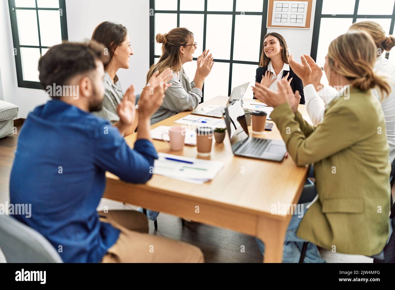 Group of business workers smiling and clapping to partner at the office ...