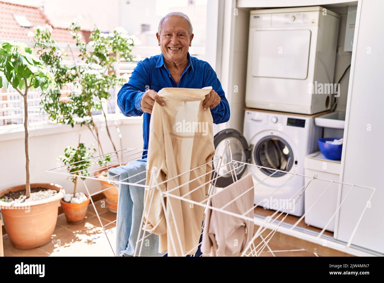 Senior caucasian man smiling happy putting clothes on clothesline at ...
