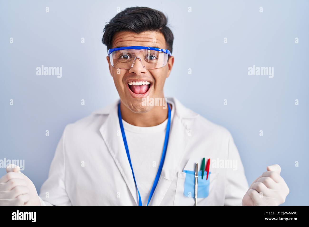 Hispanic man working as scientist celebrating surprised and amazed for ...