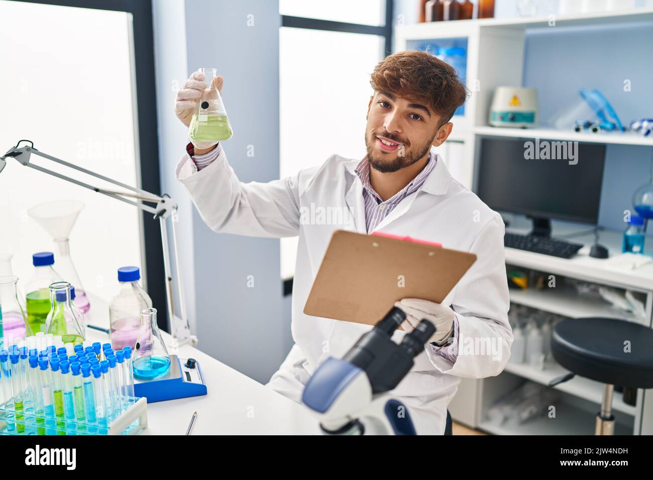 Young arab man scientist measuring liquid reading report at laboratory Stock Photo - Alamy