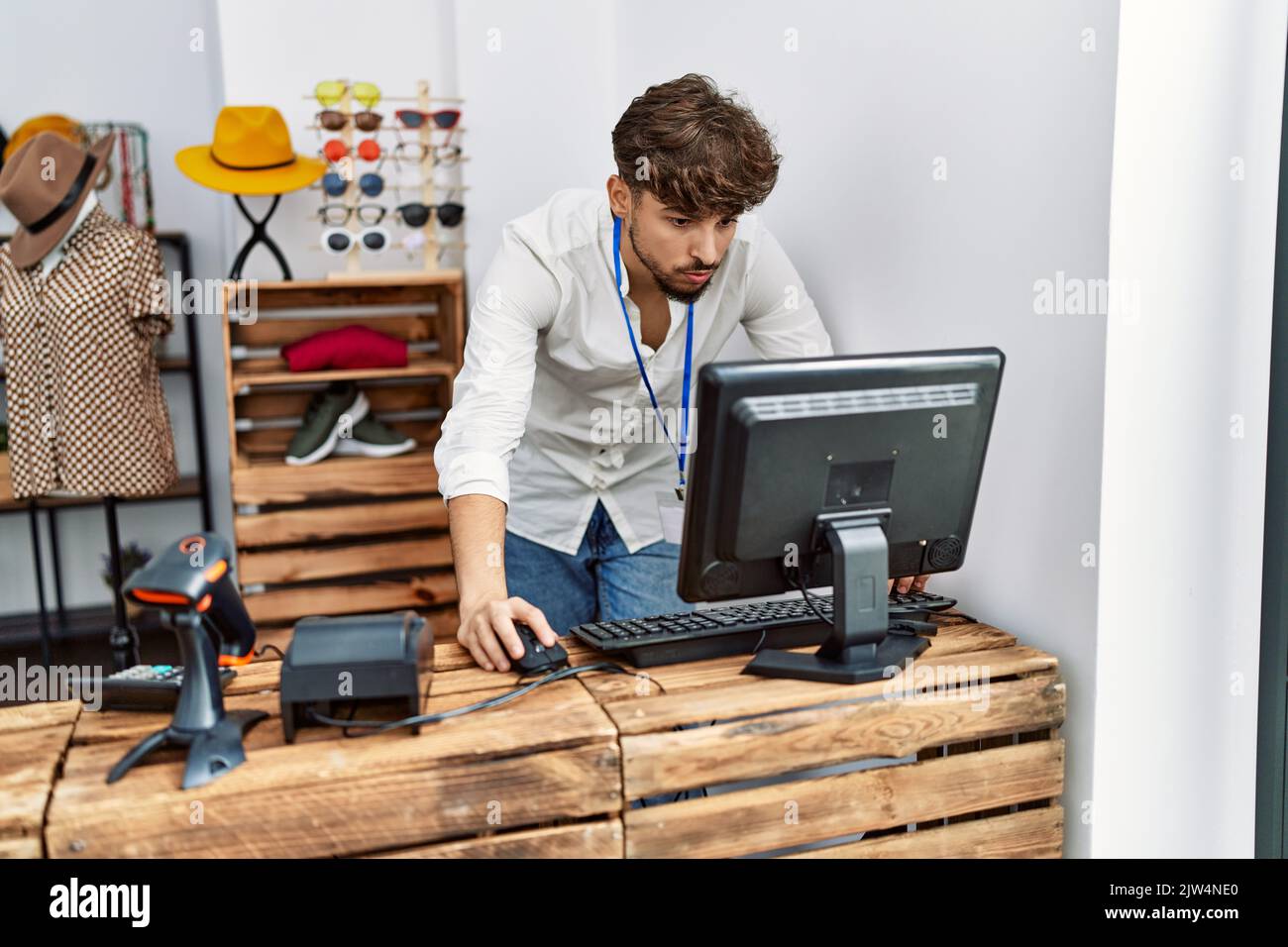 Young arab man using computer working at clothing store Stock Photo - Alamy