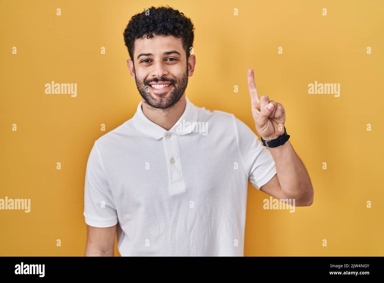 Arab man standing over yellow background showing and pointing up with ...