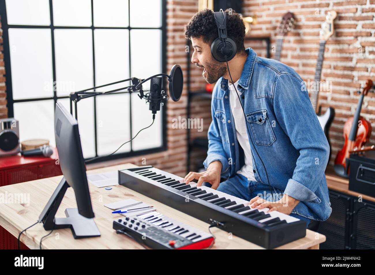 Young arab man musician singing song playing piano keyboard at music ...